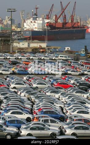 Cars for export are loaded onto a cargo ship at a port in Yokohama ...