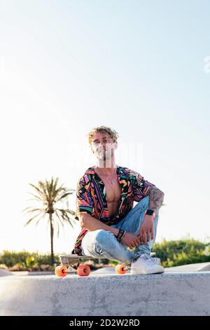 Man in stylish t-shirt and with skateboard near grey wall Stock Photo ...