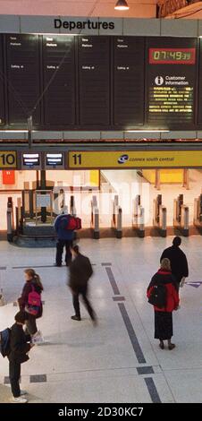 Commuters wait in front a departure board at a train station in Cologne ...