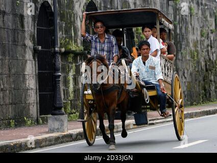 A horse drawn carriage known as a Kalesa being driven in downtown Cebu ...
