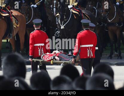 A fainting Guardsman is carried off the parade ground as The Queen ...