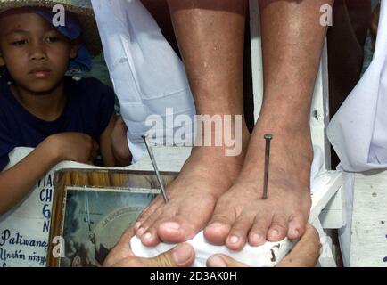 The feet of a Filipino penitent is nailed to a wooden cross during Good ...