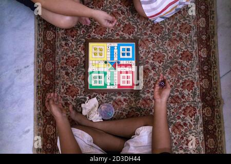 Children and adults play ludo game at home during holidays in India ...