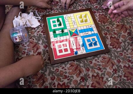 Children and adults play ludo game at home during holidays in India ...