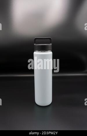 Close-up of a black thermos bottle placed on a large tree stump in the ...