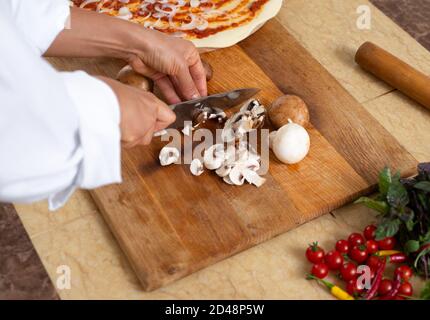 Side view of woman slicing a mushrooms on a wooden board Stock Photo ...