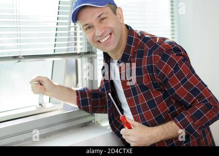 Worker adjusting installed window with screwdriver indoors Stock Photo ...
