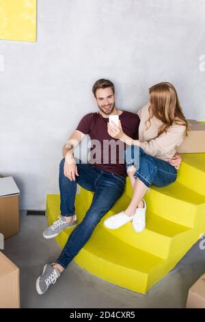 Pleased woman sitting near devices and coffee on table at home,stock ...