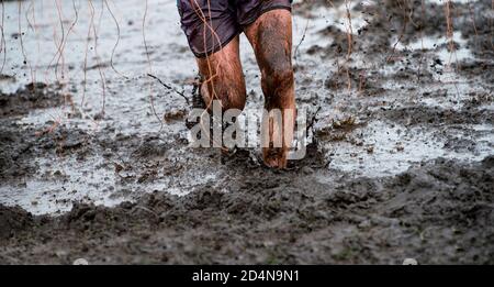 Mud race runner, man running in mud. Runners during extreme obstacle ...