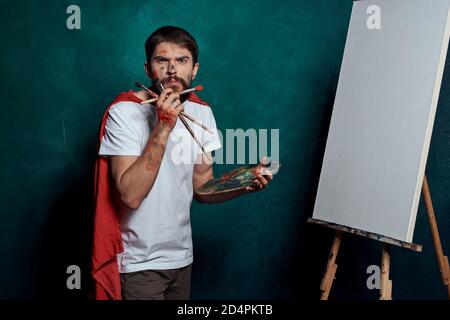 Male artist red cloak drawing easel art green background image Stock ...