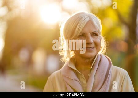 Elderly woman in autumn park doing warm up before nordic walking among ...