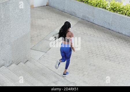 Fit african american woman running on foot bridge exercising in city ...