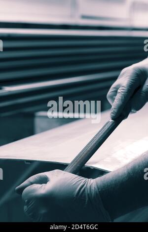 Man filing deburring a metal panel with a file. With colout toning ...