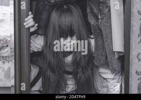 Mad scary girl in cupboard at dark night. Horror background with child ...