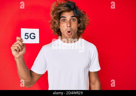 Young hispanic man holding 5g paper message smiling happy pointing with ...