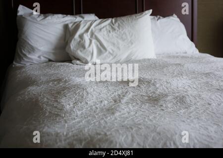 A very lumpy bed with white bedspread and pillows Stock Photo - Alamy