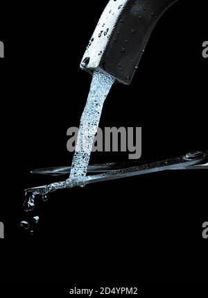 Scissors cut a stream of clean, cold water from a misted tap Stock ...