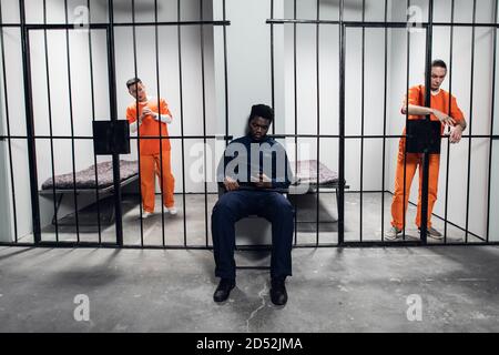 A strong black prison guard guards the cells with prisoners in the ...
