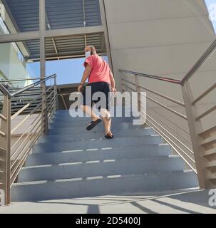 Man wearing a facemask while climbing the stairs Stock Photo - Alamy
