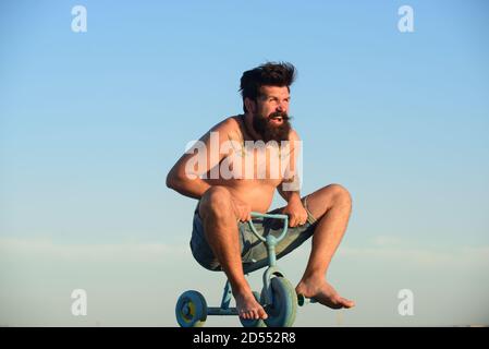 Guy riding childs tricycle. Crazy young man riding three wheeled ...