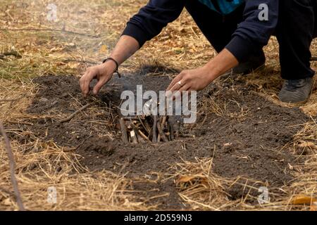 Man putting wooden sticks into fire. Bonfire in the forest. Campfire in ...