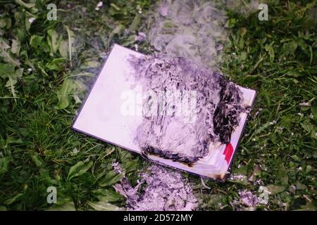 Old notepad burning on green summer grass outdoors Stock Photo - Alamy