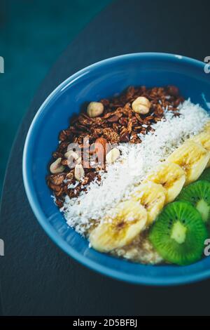 Oatmeal served in white ceramic bowl garnished with red yellow cherries ...