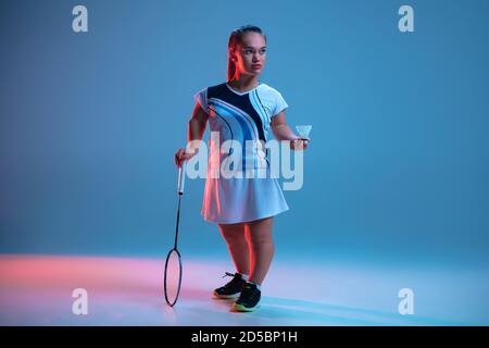 Leader. Beautiful dwarf woman practicing in badminton isolated on blue background in neon light ...
