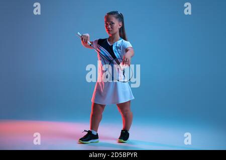 Leader. Beautiful dwarf woman practicing in badminton isolated on blue background in neon light ...