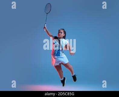 Winner. Beautiful dwarf woman practicing in badminton isolated on blue background in neon light ...
