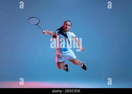 Winner. Beautiful dwarf woman practicing in badminton isolated on blue background in neon light ...