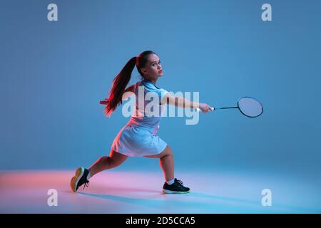Winner. Beautiful dwarf woman practicing in badminton isolated on blue background in neon light ...
