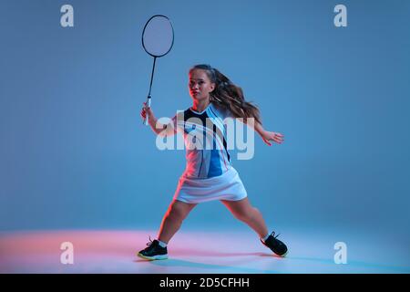 Energy. Beautiful dwarf woman practicing in badminton isolated on blue background in neon light ...