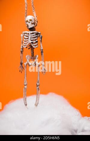 Fake skeleton on a rope in the background on an orange background ...