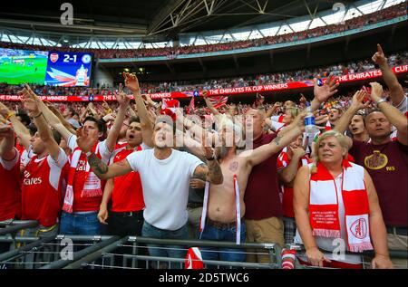 Arsenal fans celebrate on the side of street and on a bus shelter as ...