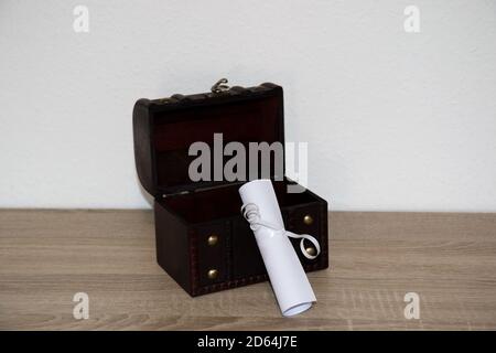 Opened treasure chest next to a blank rolled paper Stock Photo - Alamy