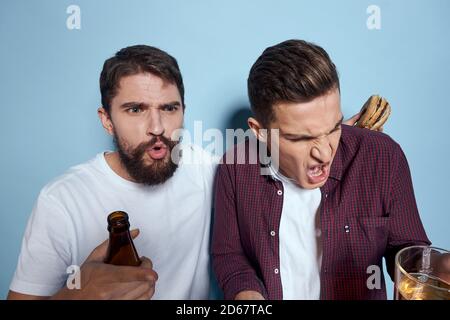 Two cheerful drunk friends drinking beer lifestyle emotions on a blue ...