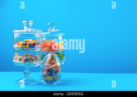 Glass containers with colorful candies against blue background Stock ...
