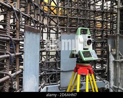 Total station theodolite tool on a tripod at construction site among ...