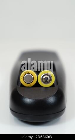 Black remote control with yellow AAA batteries on a white background ...