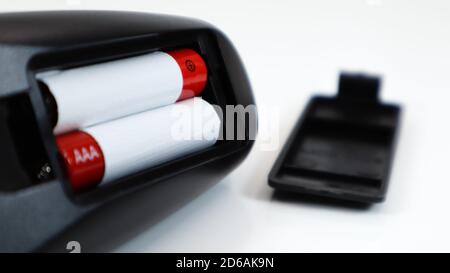 Black TV remote control with AAA alkaline batteries on a white ...