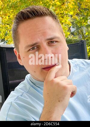 Young man looking intently at the camera with a quiet thoughtful smile ...