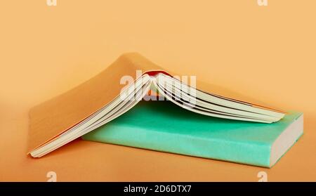 Two books with colored covers are on a uniform orange background Stock ...