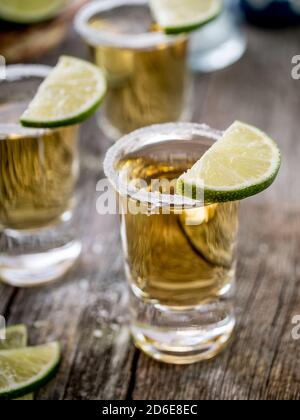 Tequila shots served with salt rim and lime wedges on a grunge wooden ...