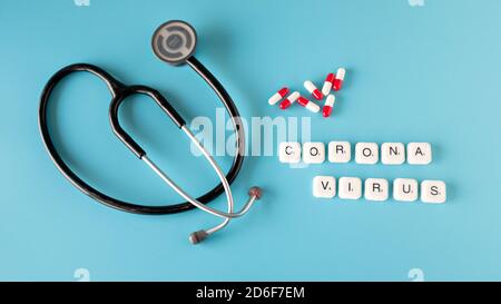 Closeup shot of "Coronavirus" cubic letters, capsule medications, and a ...
