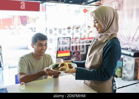 a man give a dish traditional food to woman Stock Photo - Alamy