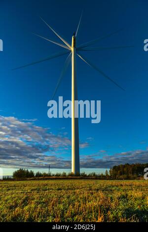 wind generator in white rotates on a background of blue sky with clouds ...