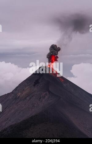Glowing lava and smoke spitting volcano, volcanic eruption at night ...