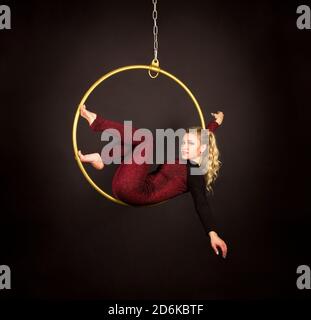 Aerial performer in a gold costume suspended against a vibrant sunset ...