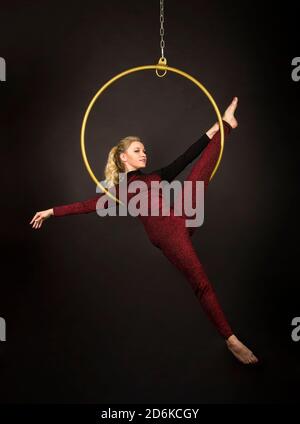 Aerial performer in a gold costume suspended against a vibrant sunset ...